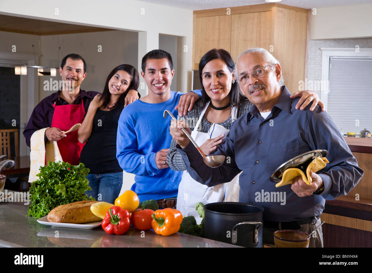 Three generations, Hispanic family cooking together in kitchen at home ...