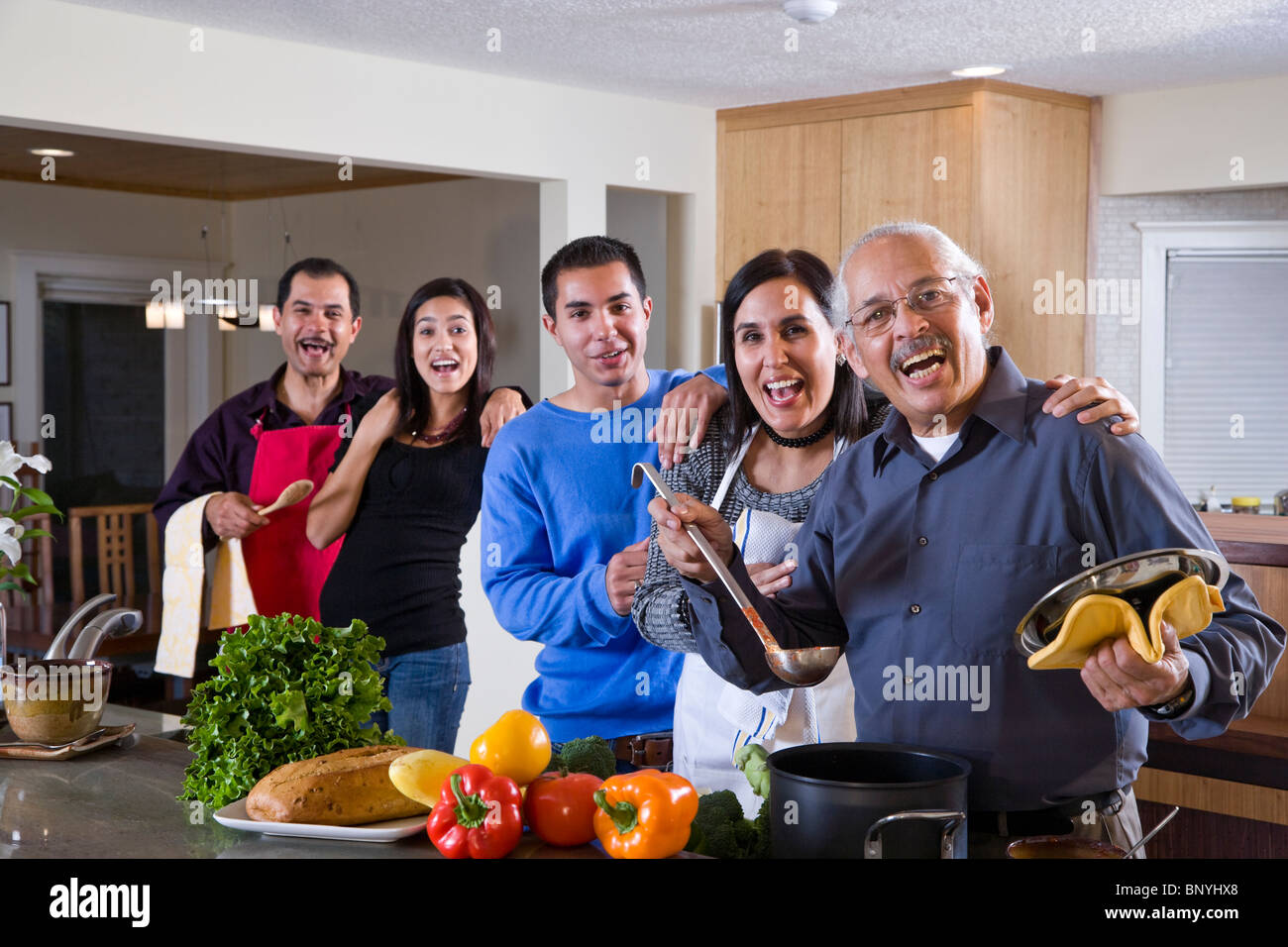 Three generations, Hispanic family cooking together in kitchen at home ...