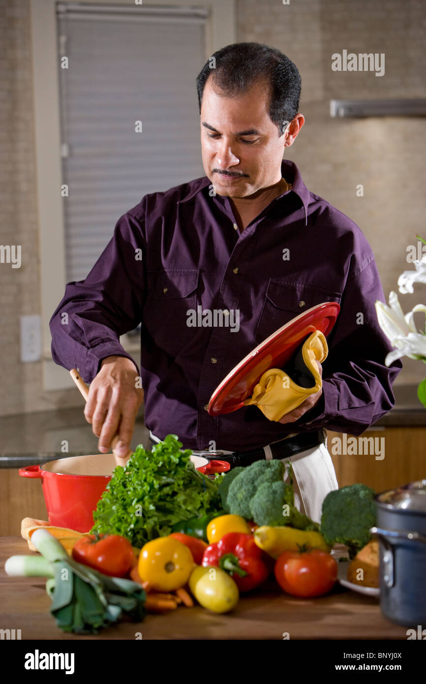Mature Hispanic man cooking healthy meal at home in kitchen Stock Photo ...