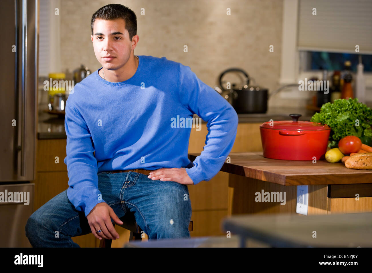 Serious Hispanic teenage boy thinking at home in kitchen Stock Photo ...