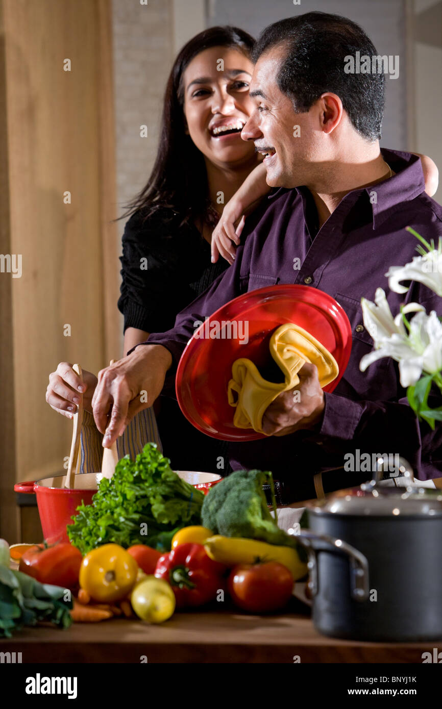 Hispanic father and teenage daughter cooking at home in kitchen Stock ...