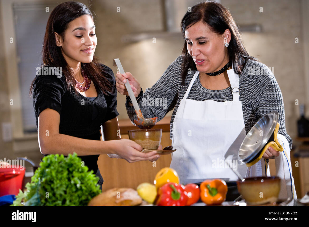 Hispanic mother and teenage daughter cooking at home in kitchen Stock ...