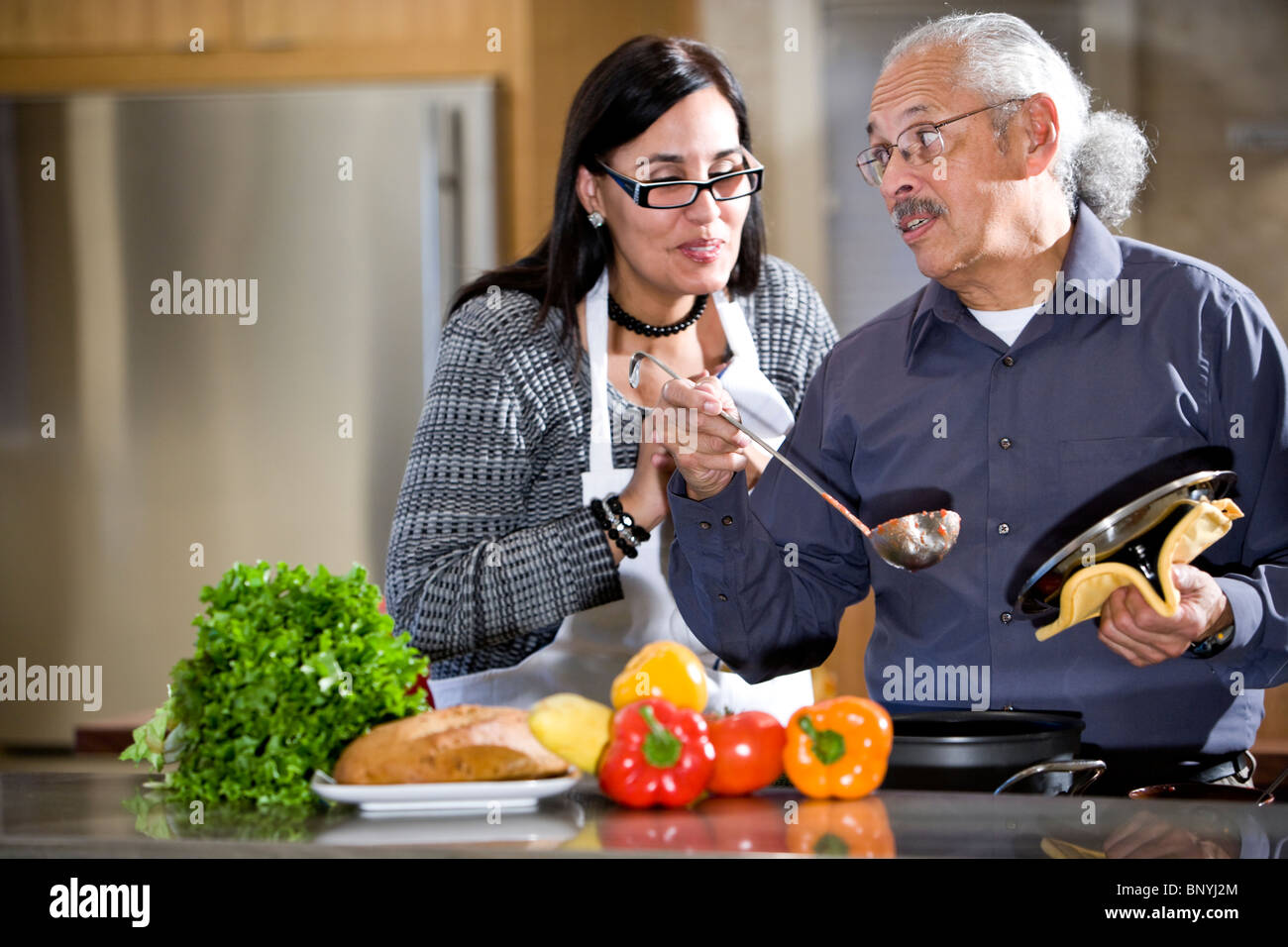 Senior Hispanic man and adult daughter cooking in kitchen Stock Photo ...
