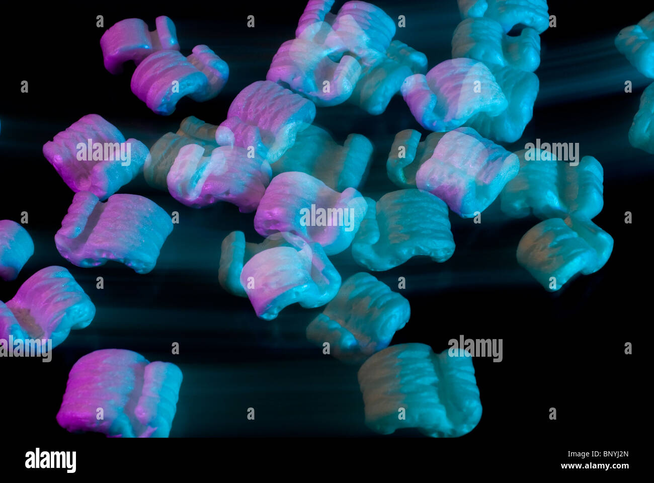purple and blue styrofoam packaging peanuts moving on black background ...