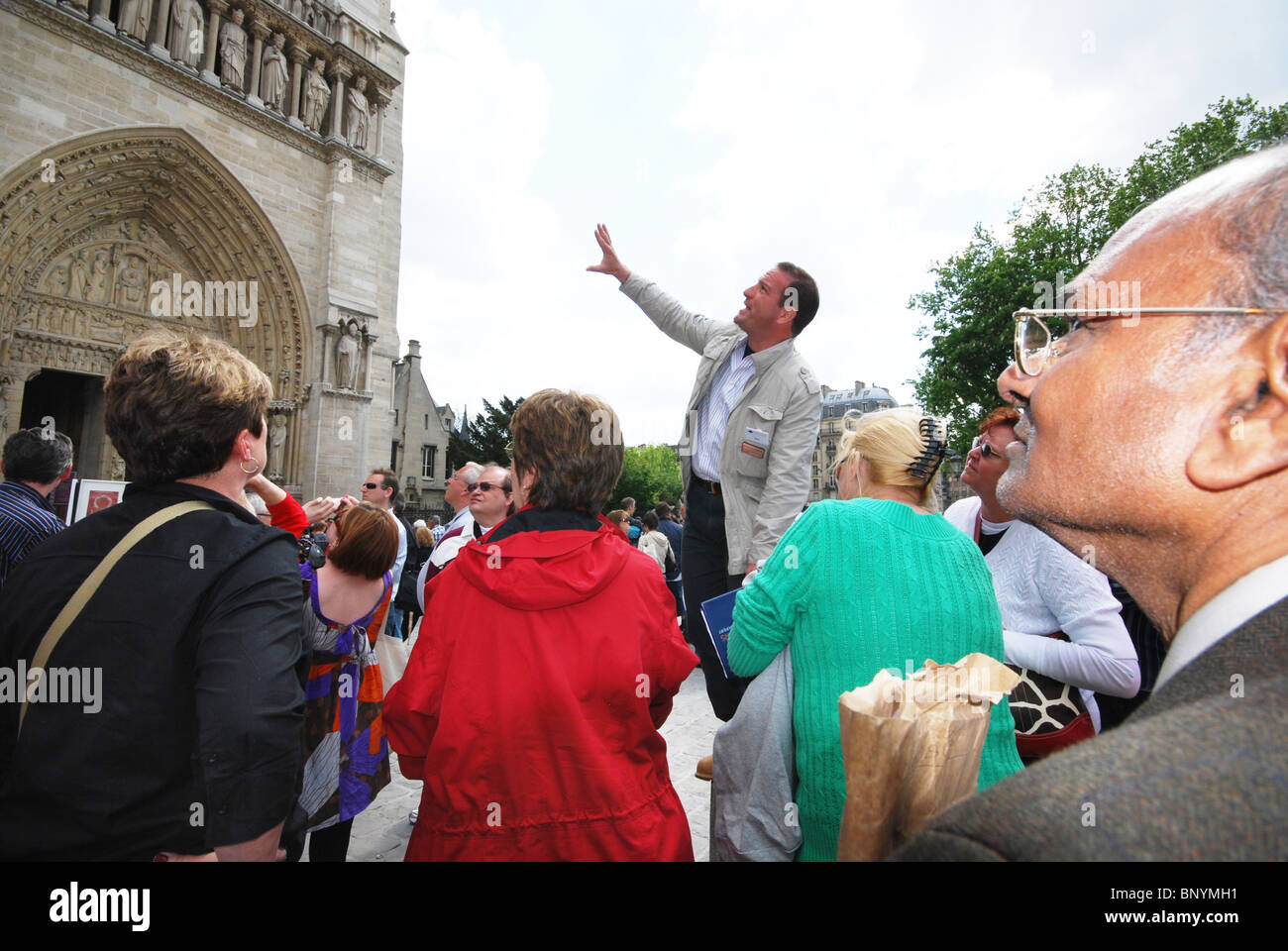 crowd of tourists listening to tour guide in front of Notre Dame Paris ...