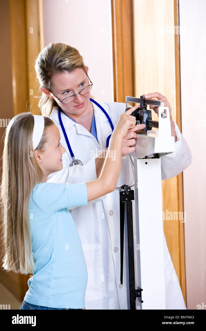 Doctor weighing young girl on scale Stock Photo - Alamy