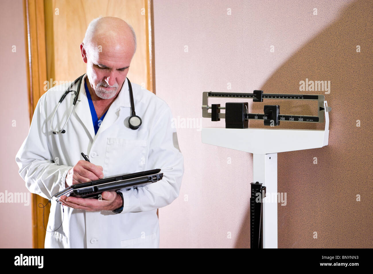 Doctor looking at patient chart writing notes Stock Photo - Alamy