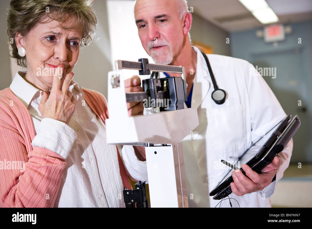 Doctor weighing senior woman on scale Stock Photo - Alamy