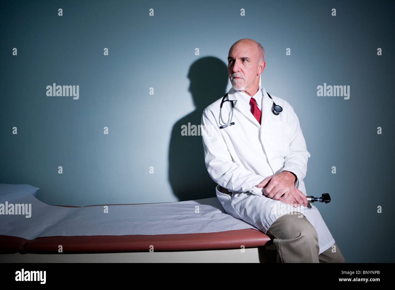 Doctor alone in exam room thinking Stock Photo - Alamy