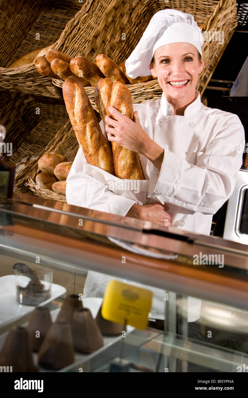 Baker with loaves of bread behind bakery counter Stock Photo - Alamy