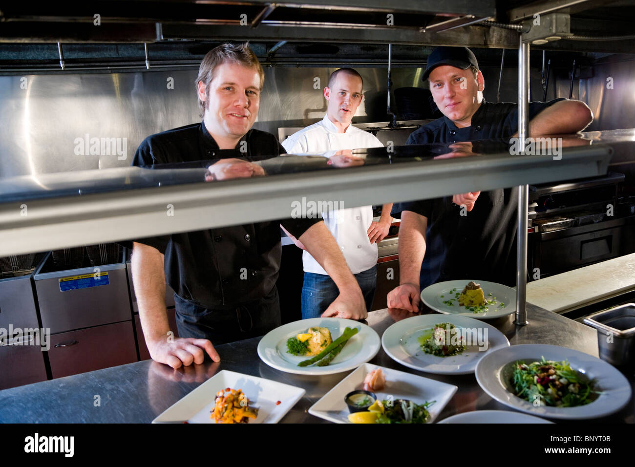 Chefs in restaurant kitchen with plates of prepared dishes Stock Photo ...