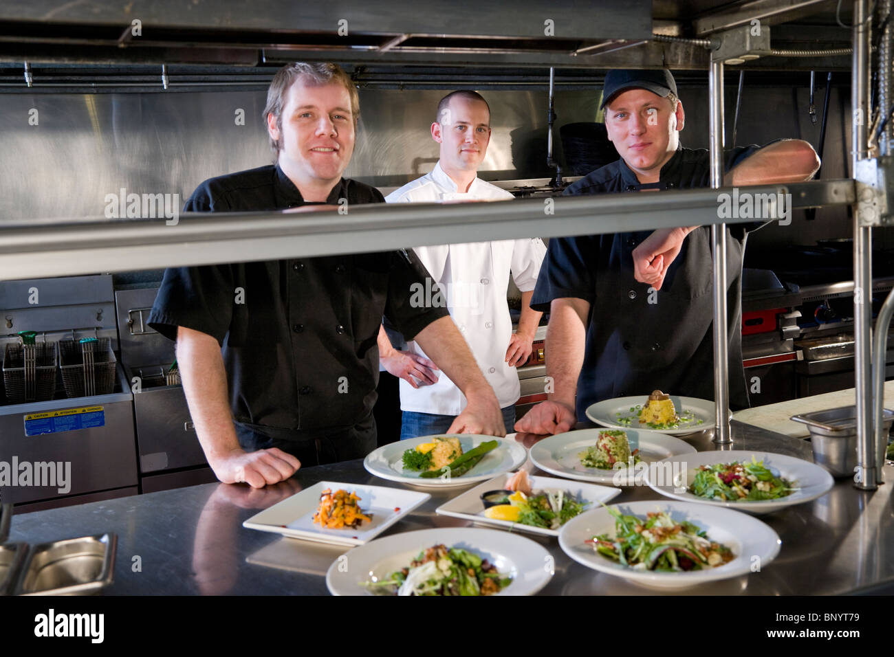 Chefs in restaurant kitchen with plates of prepared dishes Stock Photo ...