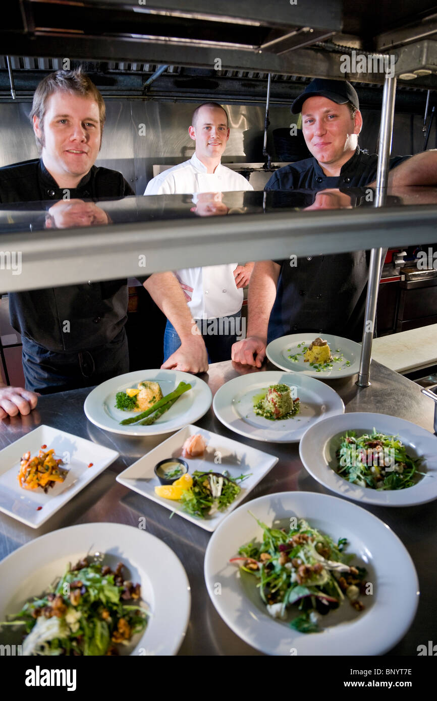 Chefs in restaurant kitchen with plates of prepared dishes Stock Photo ...