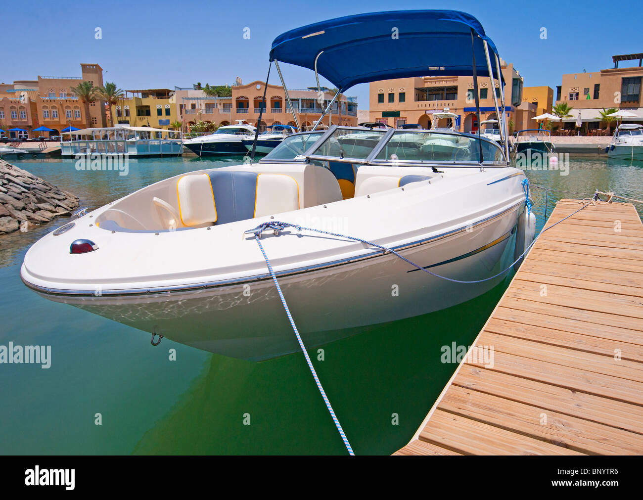 A luxury speedboat moored to a private jetty in a tropical marina Stock ...