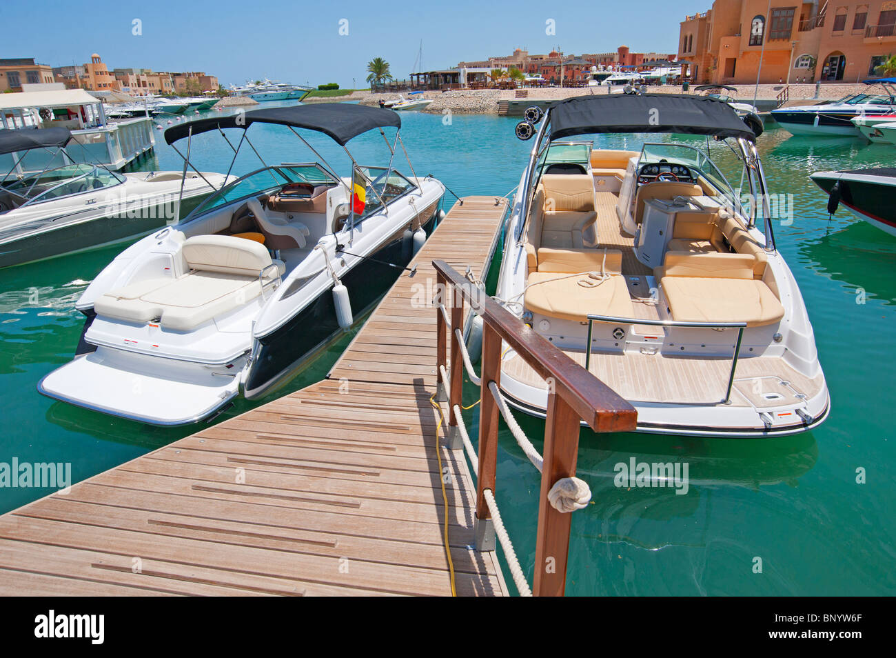 Two private motor boats moored to a wooden jetty in a tropical marina ...
