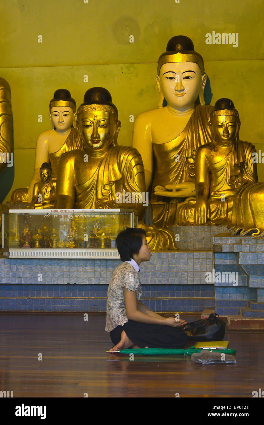 pilgrim praying inside small pavilion with Buddha statues, Shwedagon ...