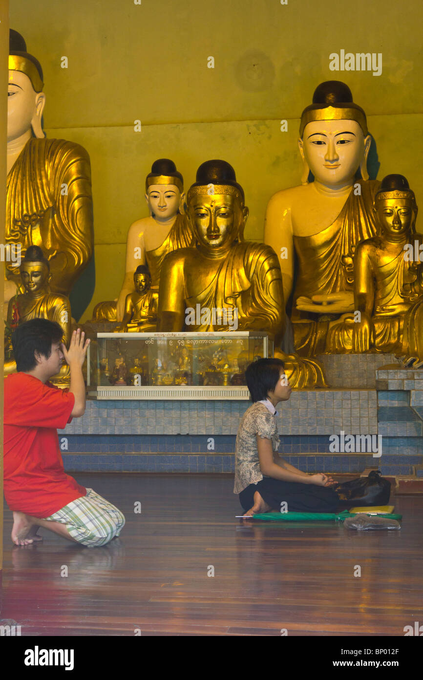 pilgrims praying inside small pavilion with Buddha statues, Shwedagon ...