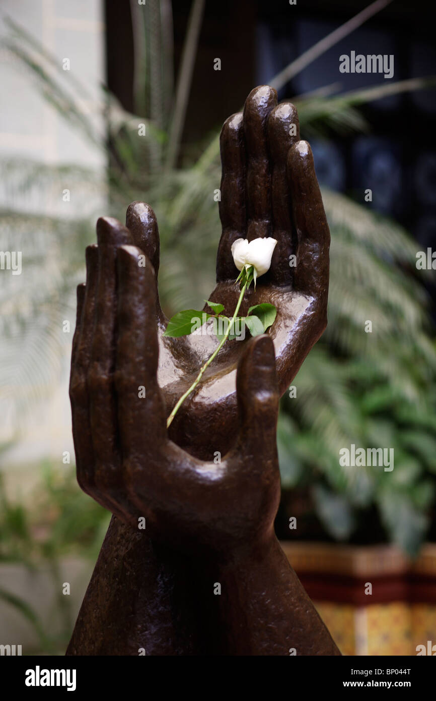 A white rose symbolising peace is held in a stone sculpture of two ...