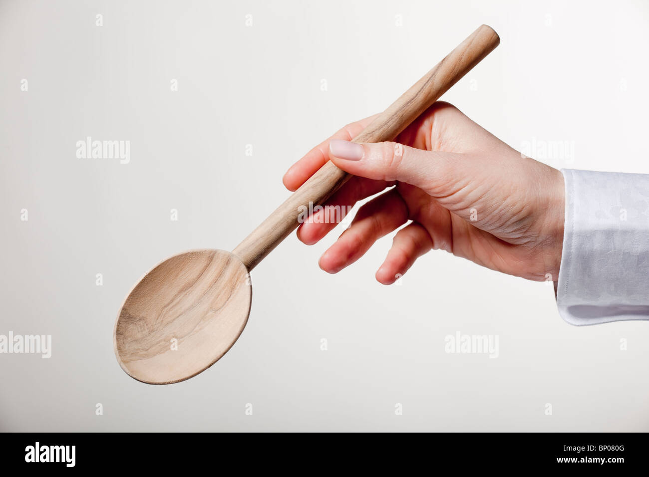 Female hand holding wooden spoon isolated on light background Stock ...