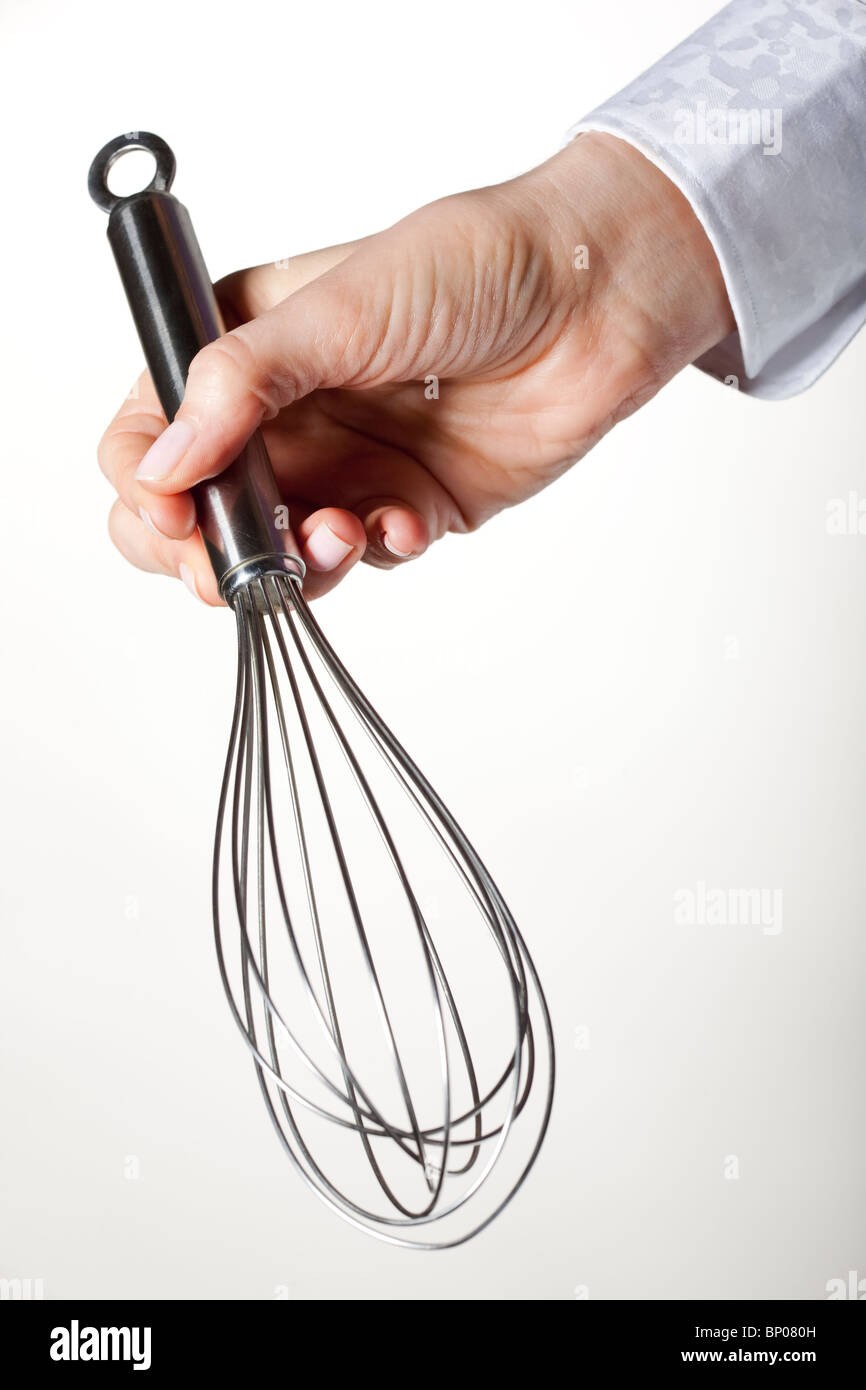 Female hand holding stainless steel whisk isolated on light background ...