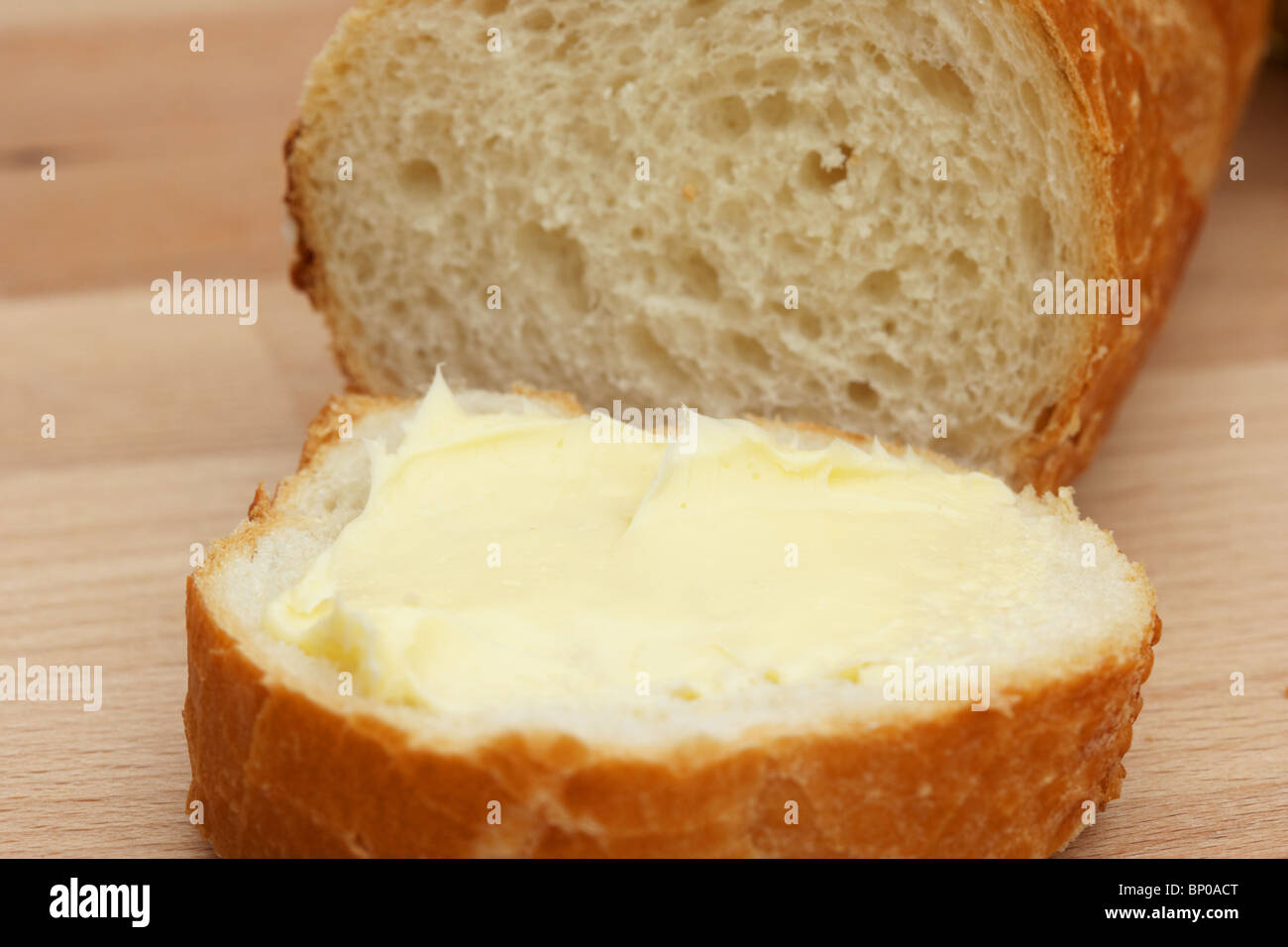 small french baton bread sliced with buttered slice on a wooden block ...