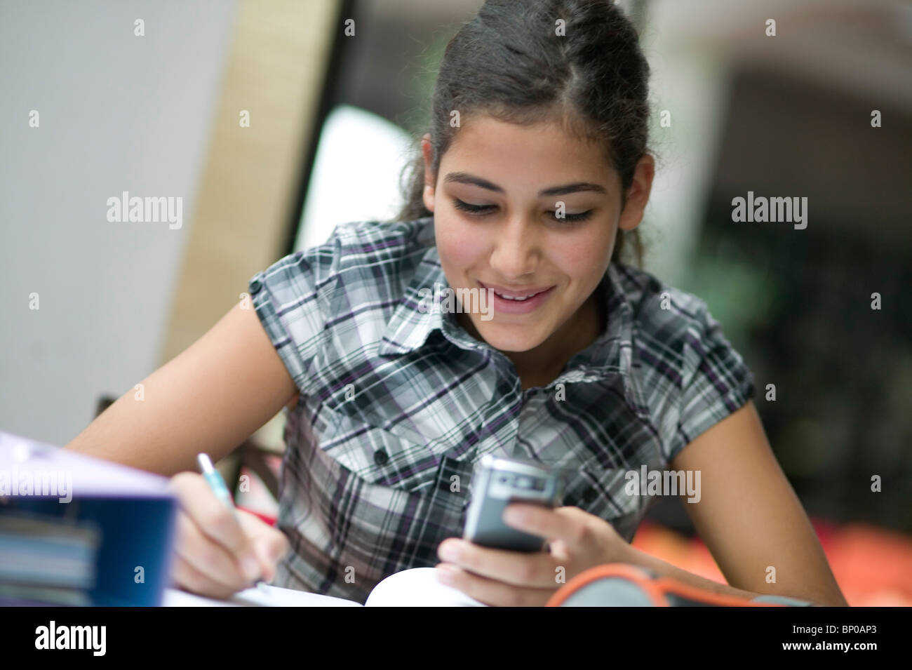Girl using mobile phone while doing homework Stock Photo - Alamy