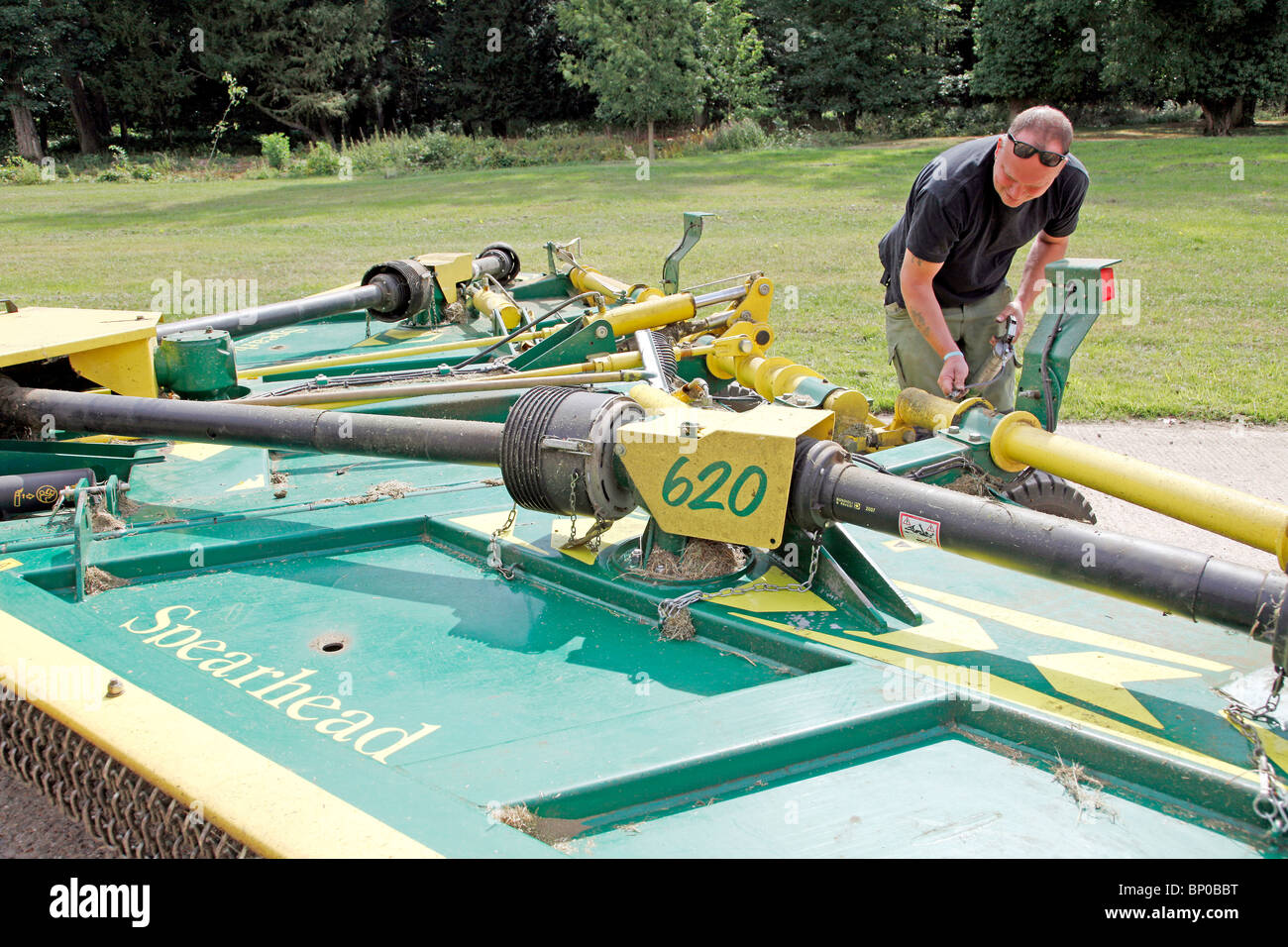 A man lubricating farm equipment before use Stock Photo - Alamy