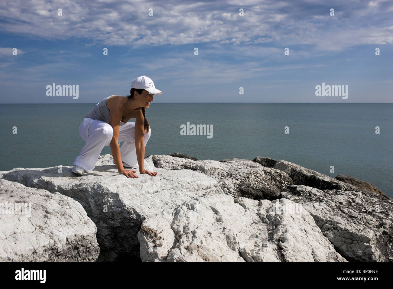 Woman hunkering down on rocks Stock Photo - Alamy