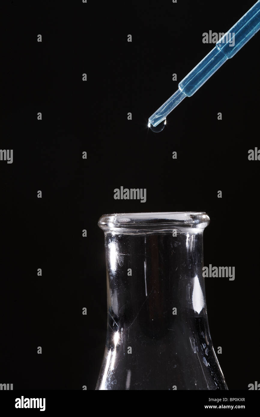 Drop of blue liquid on the end of a pipette over a flask Stock Photo ...