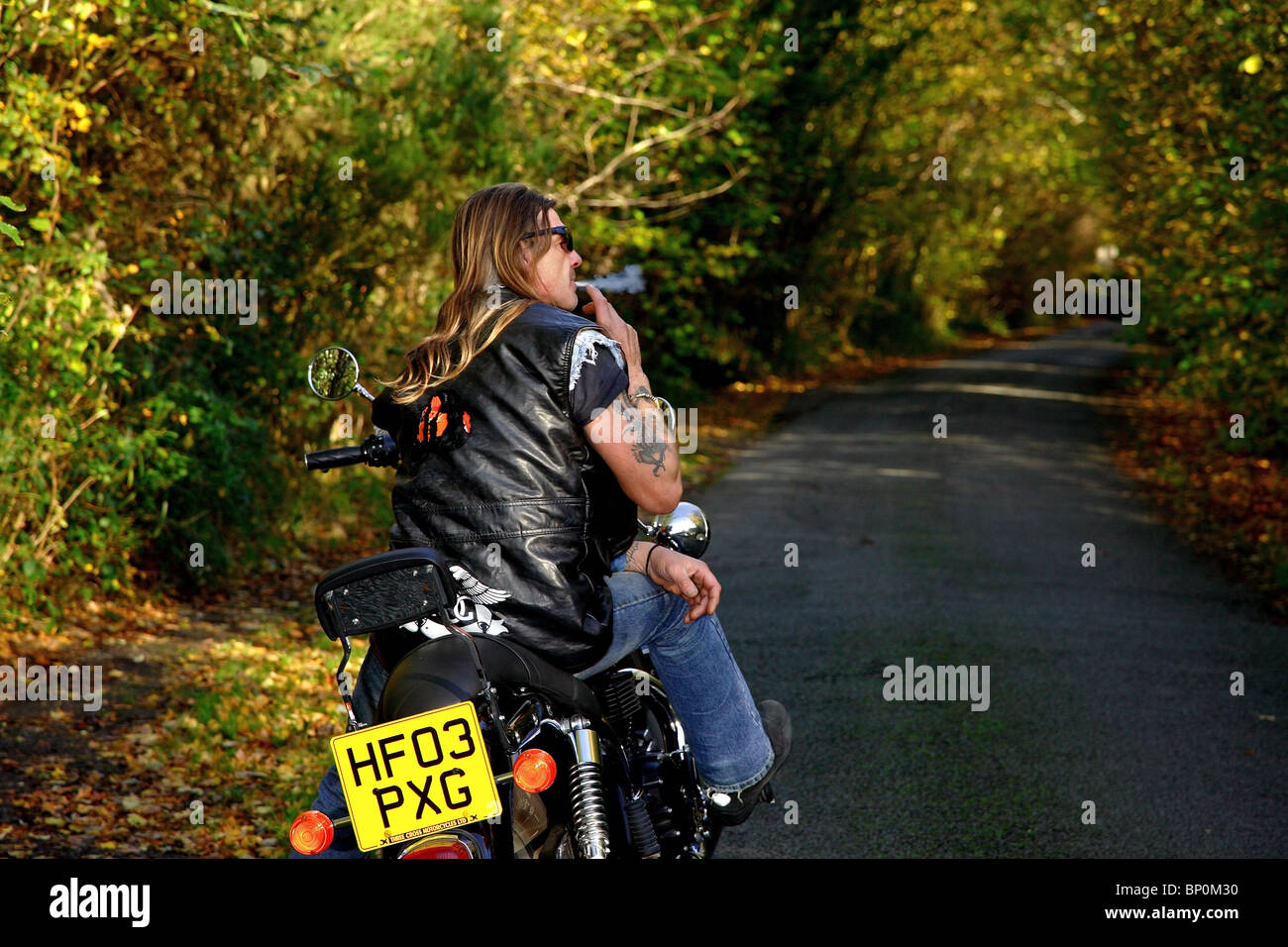 Biker in Autumn on a Country Lane Smoking a cigarette Stock Photo - Alamy