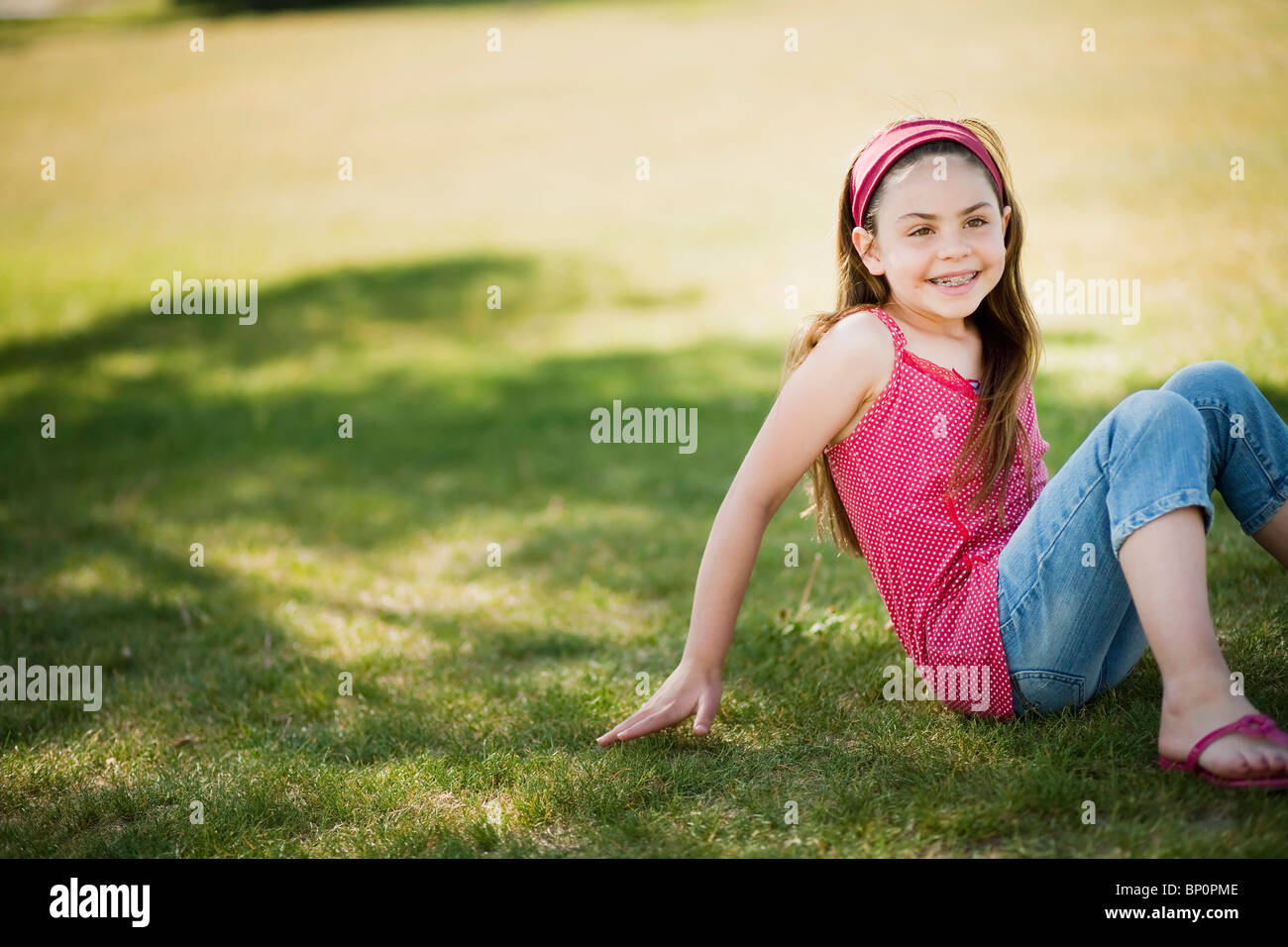 Young girl sitting on grass laughing Stock Photo - Alamy