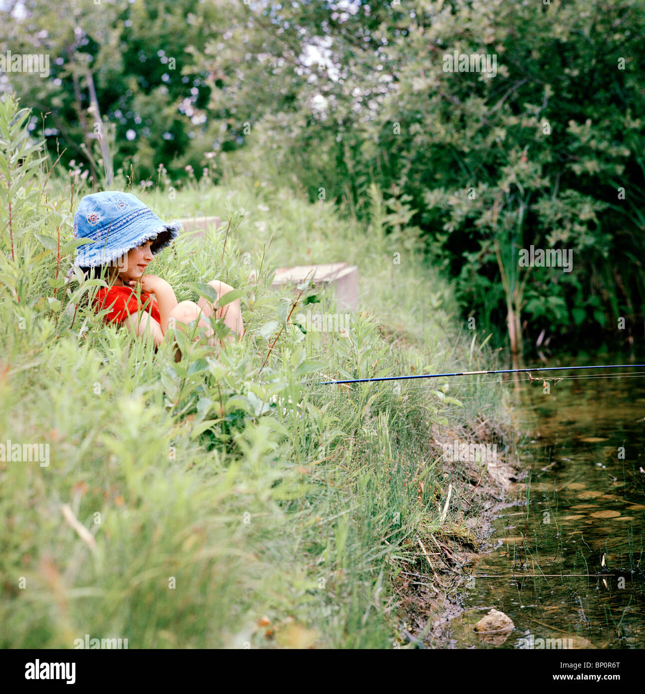 Young Girl is fishing on a country pond in rural country setting Stock ...
