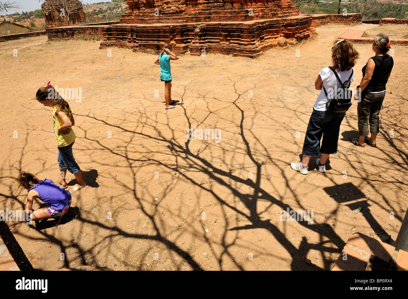 Two women and three children in shadow of a tree, in the grounds of the ...