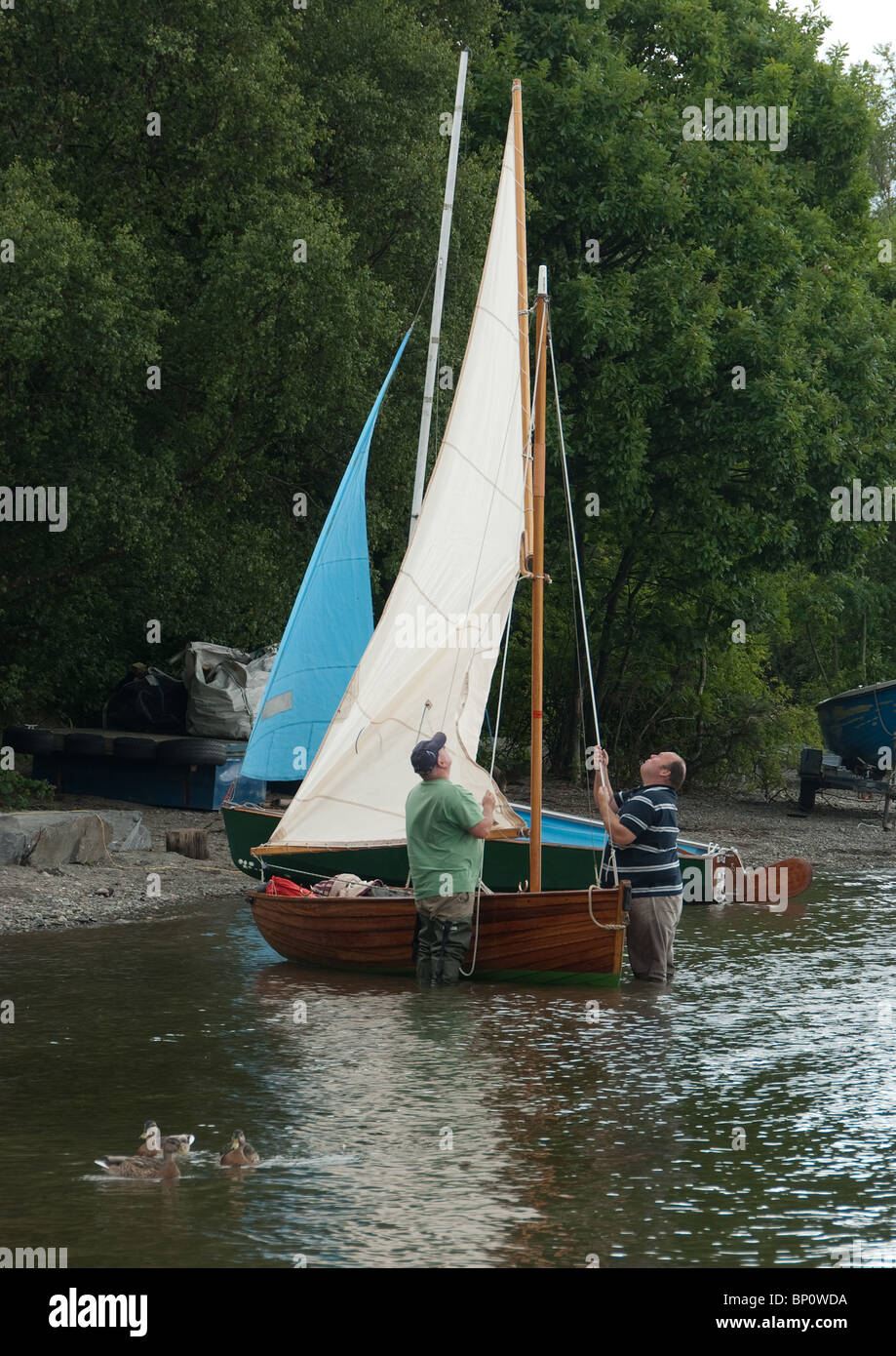Two men hoisting sails on dinghy Stock Photo - Alamy