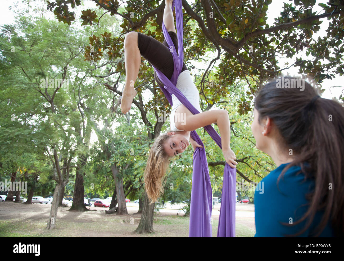 Two young woman doing acrobatics in tree Stock Photo - Alamy