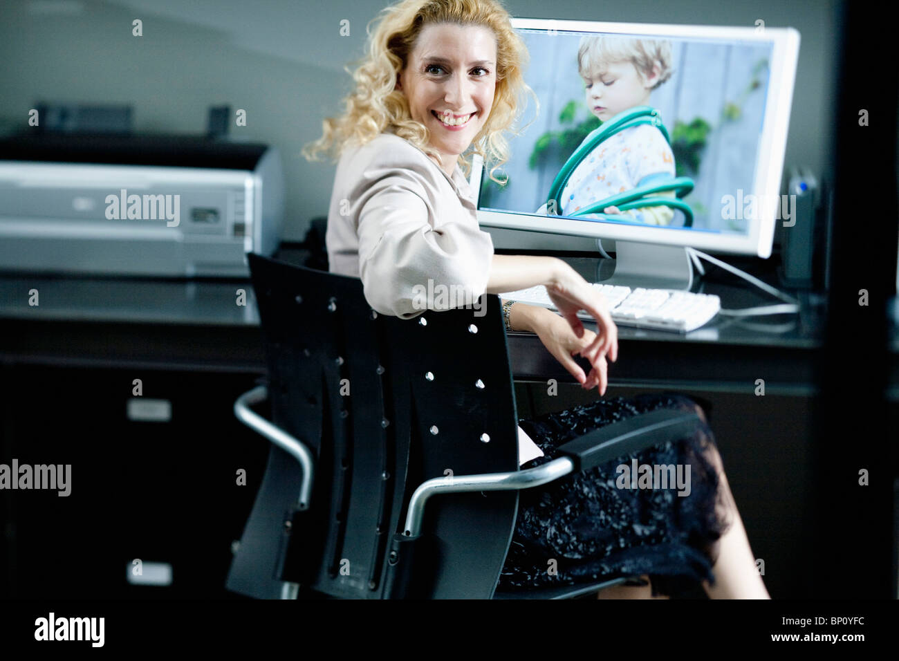 Woman smiling at her desk Stock Photo - Alamy