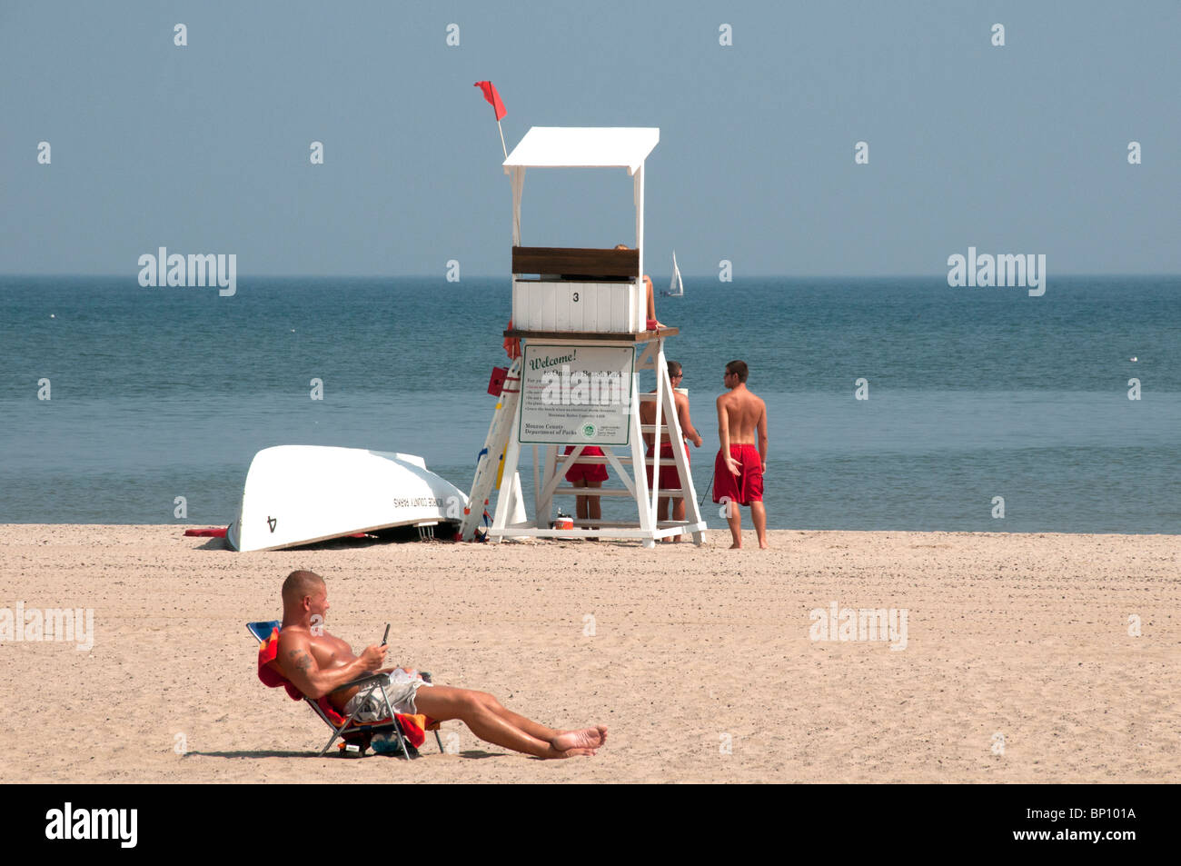 Lifeguard and sun bather on beach Stock Photo - Alamy