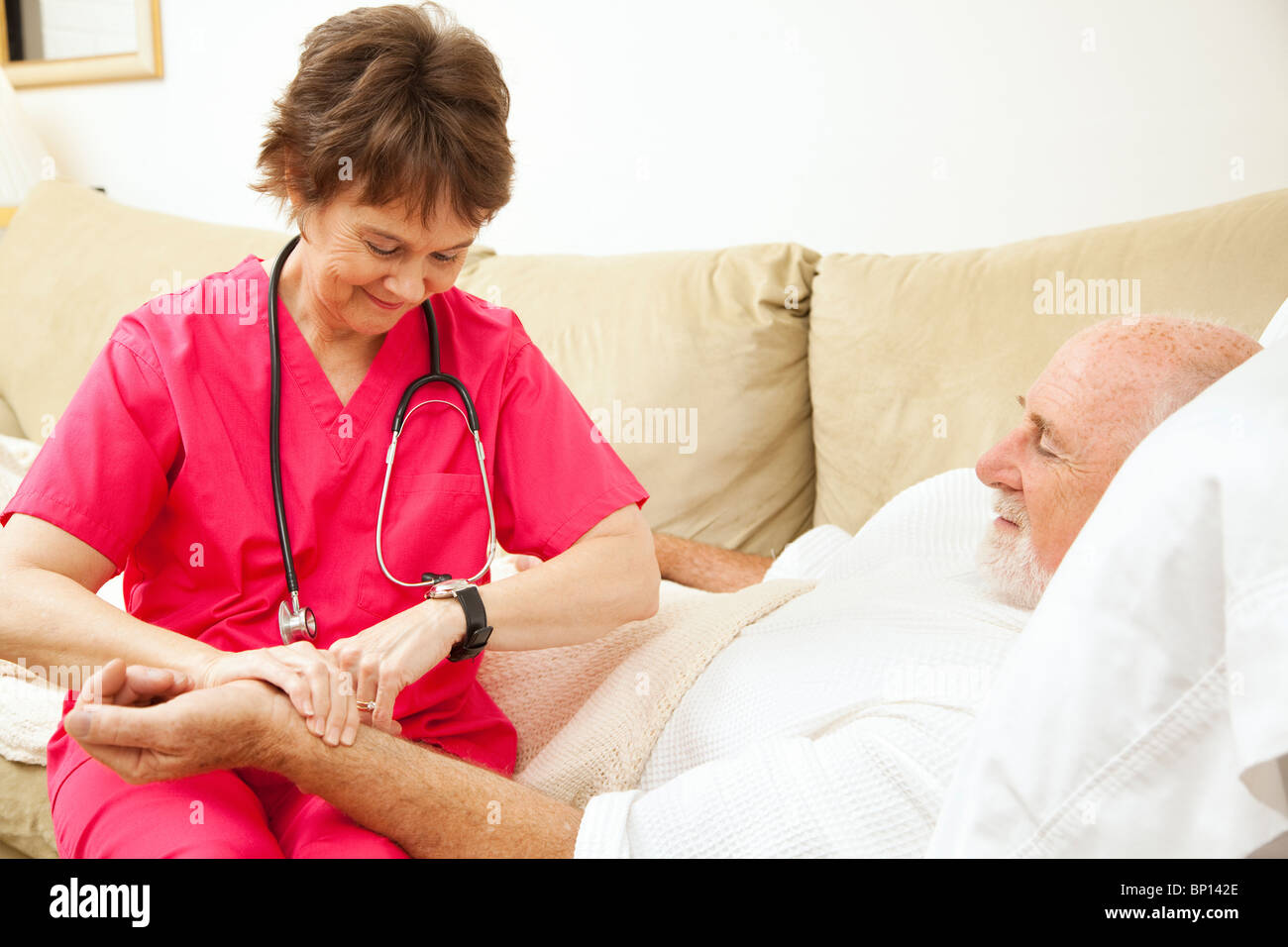 Home health nurse taking the pulse of an elderly, home-bound patient ...