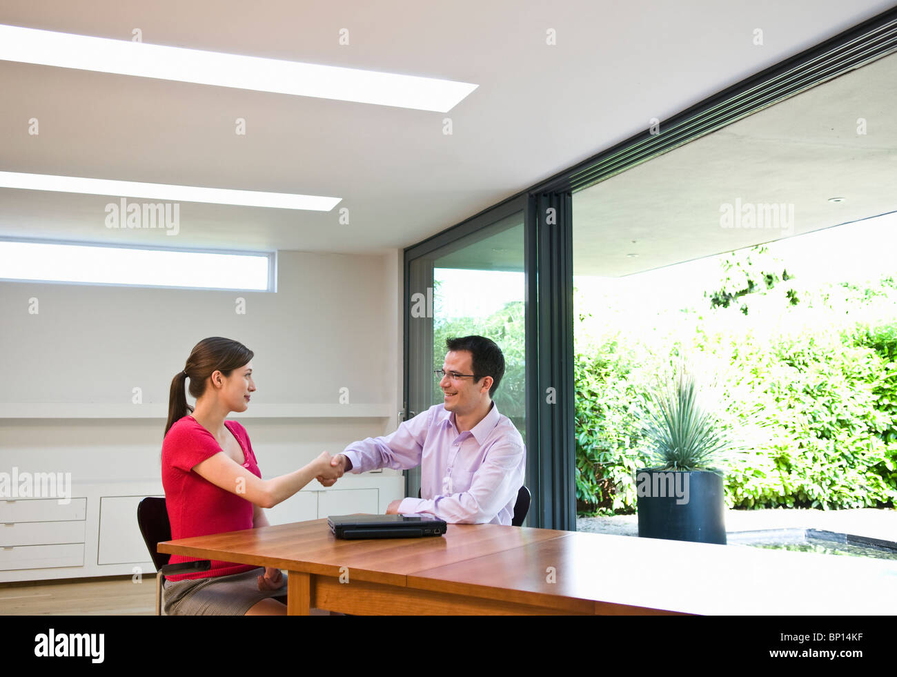 Man & woman shake hands over table Stock Photo - Alamy