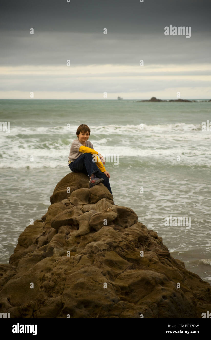 A Boy Sits On A Rock At The Water's Edge Stock Photo - Alamy