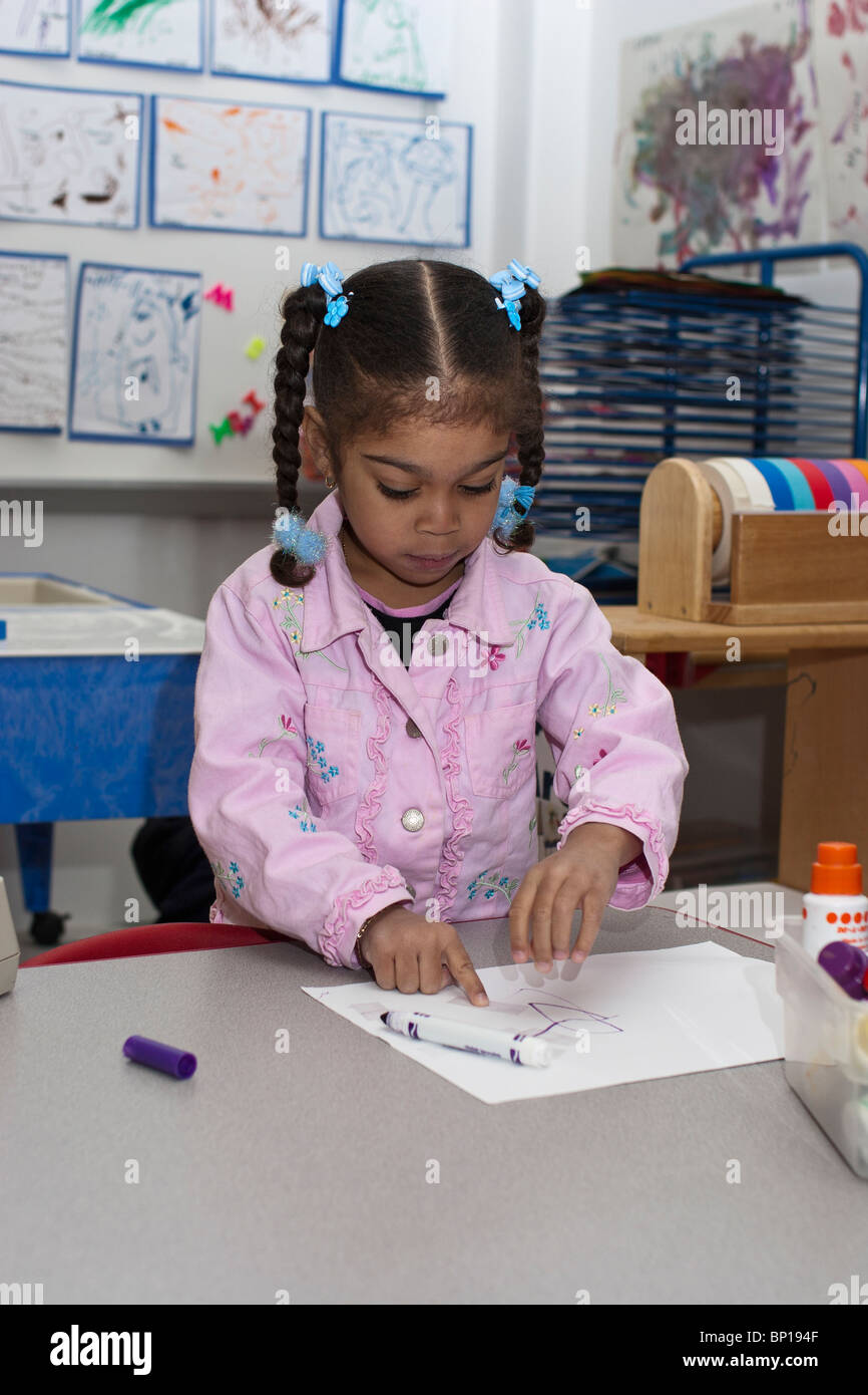 4 year old preschool girl working on an art project in the classroom ...