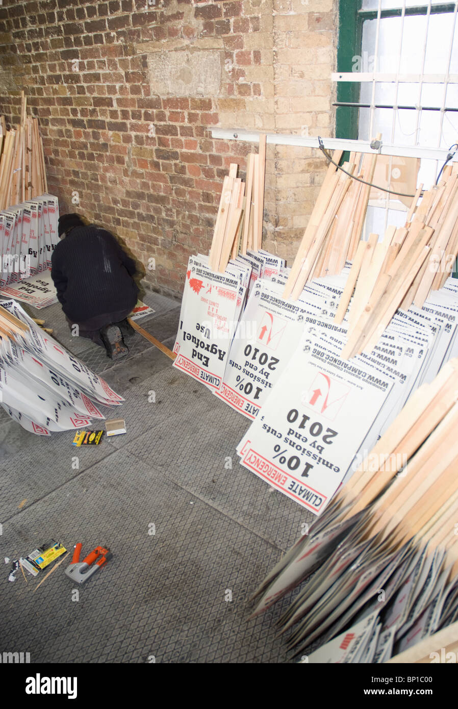 a volunteer staples placards to wooden sticks for the climate rally ...