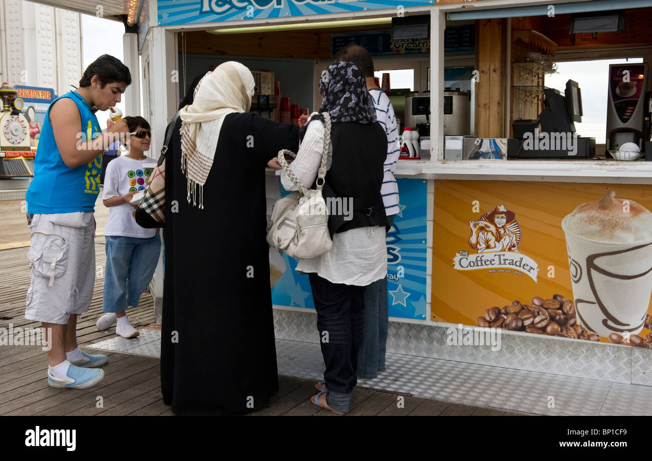 A Muslim family buying ice cream at a small shop on Brighton pier ...