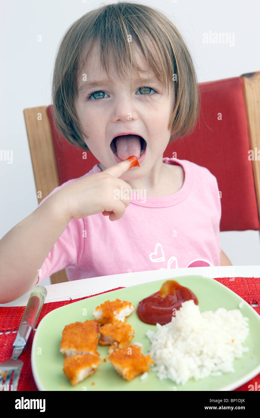 Little girl eating breaded fish and rice Stock Photo - Alamy