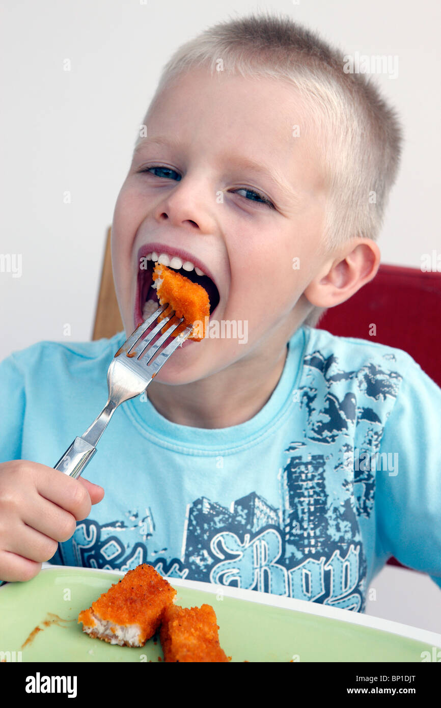 Little boy eating breaded fish Stock Photo - Alamy