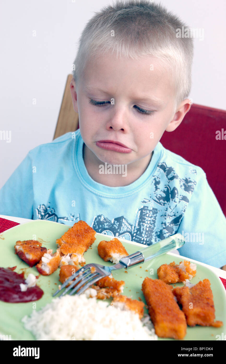 Little boy eating breaded fish and rice Stock Photo - Alamy