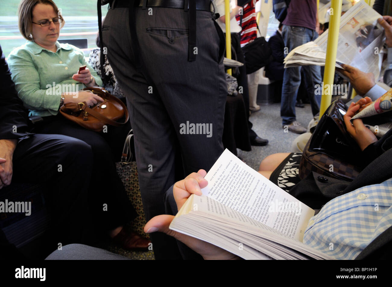LONDON UNDERGROUND PASSENGERS READING AT RUSH HOUR ON A TRAIN IN THE ...