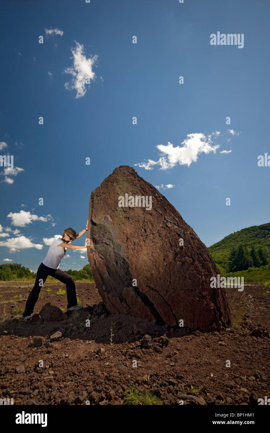 A young woman attempting to shake a spindle-shaped volcanic bomb ...