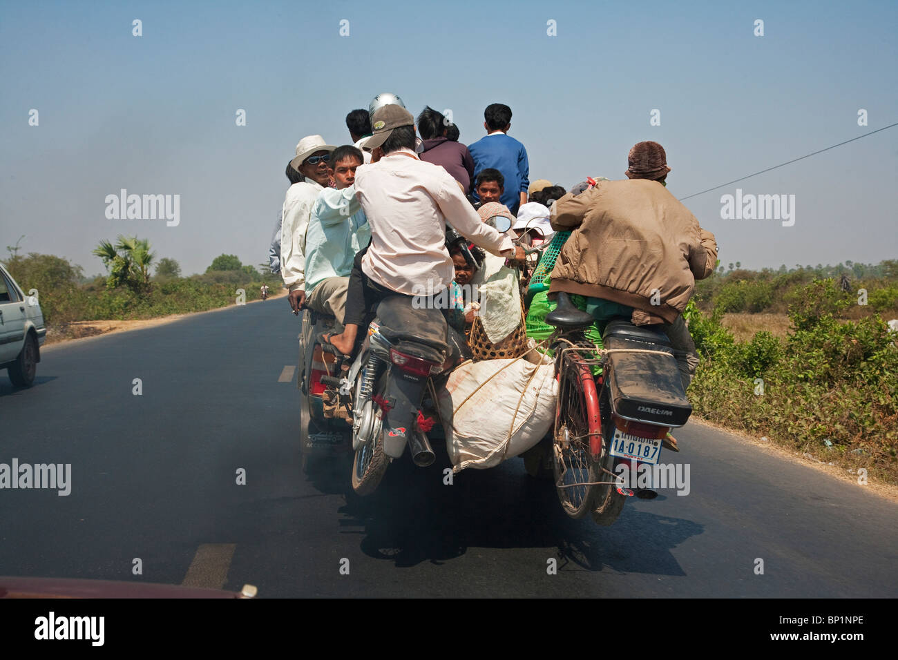 Men and motorcycles crowd onto a truck riding along the road in rural ...