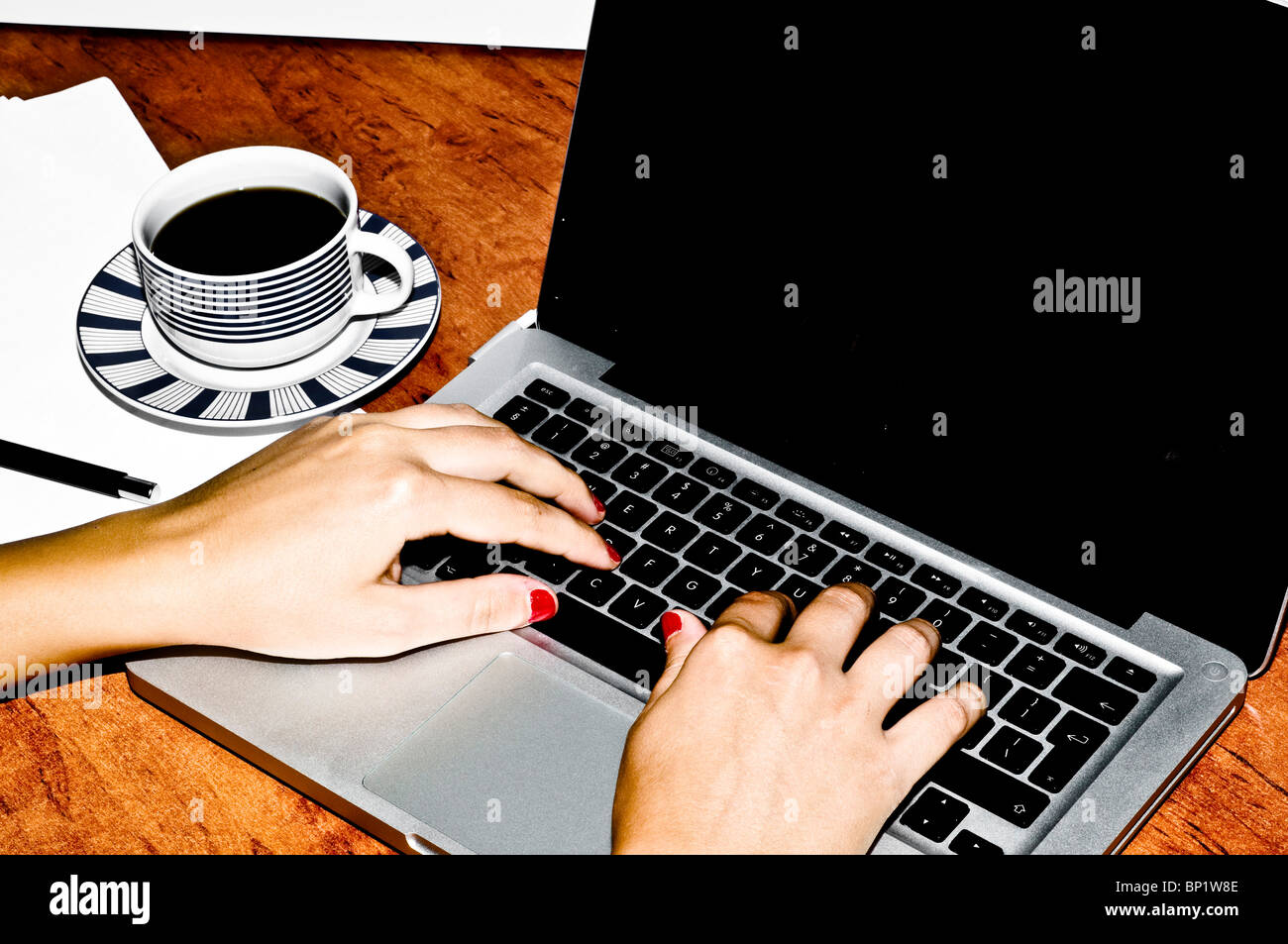 Woman typing on the laptop keyboard in office, coffee and papers in ...